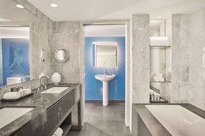 Uma casa de banho moderna com duas lavatórios, um espelho grande e uma banheira.