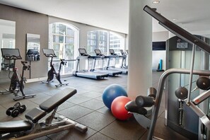 Academia com esteiras, aparelhos de musculação e bolas de exercício.