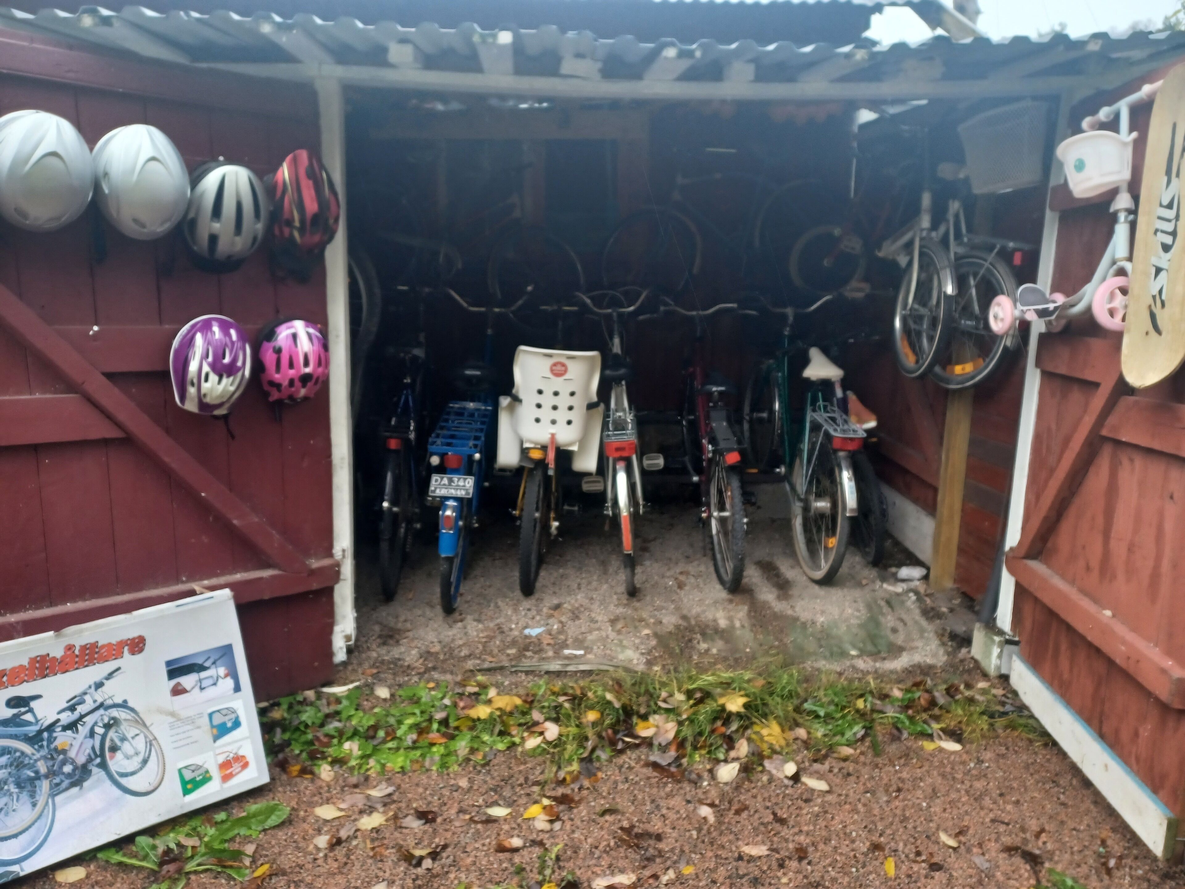 Uma área coberta para guardar bicicletas, com capacetes e bicicletas.