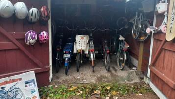 Uma área coberta para guardar bicicletas, com capacetes e bicicletas.