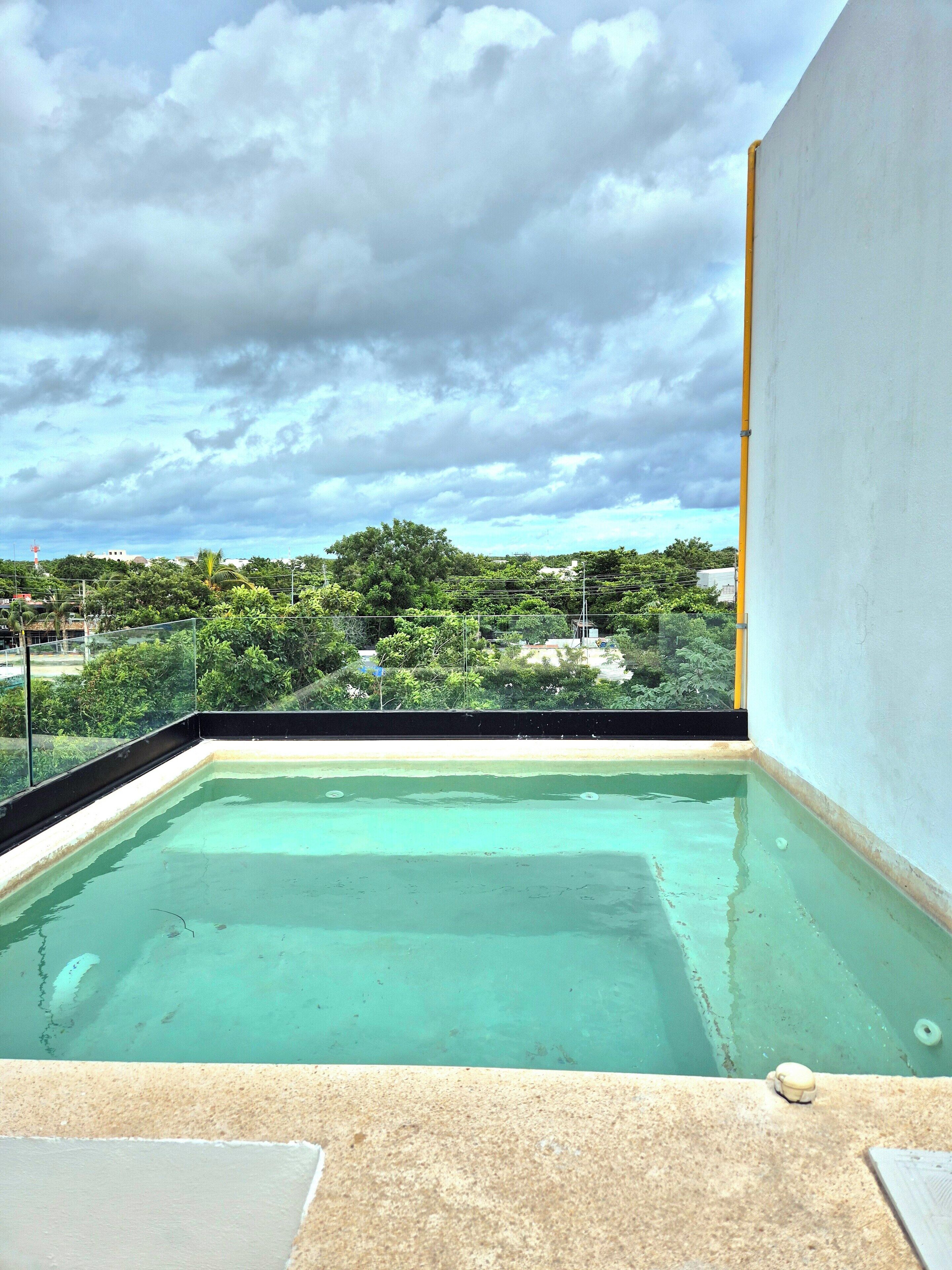 Piscina no terraço com vista ampla da paisagem urbana e áreas verdes ao redor.