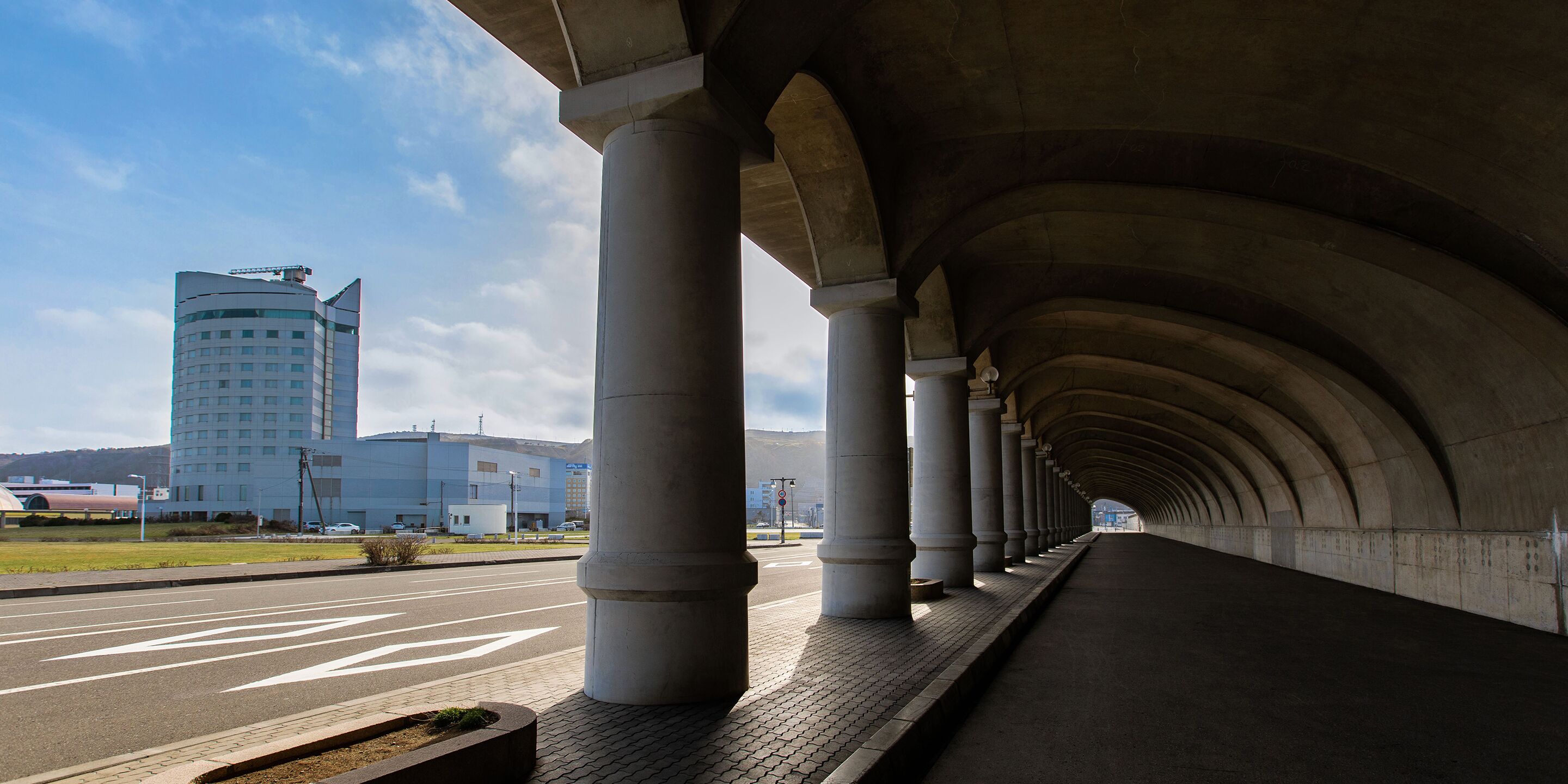 Uma passarela coberta com vista desobstruída para a rua e edifícios ao fundo.