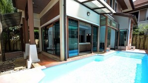 Uma casa moderna com piscina, grandes portas de vidro e um espaço de varanda coberto.
