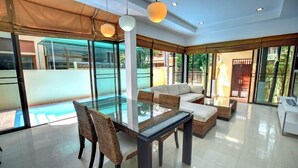 Uma sala de estar moderna com uma mesa de jantar de vidro, cadeiras de vime, um sofá e uma mesa de centro.