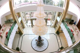Um átrio com vários níveis, uma estrutura decorativa central, guarda-corpos de vidro e uma área de estar circular.