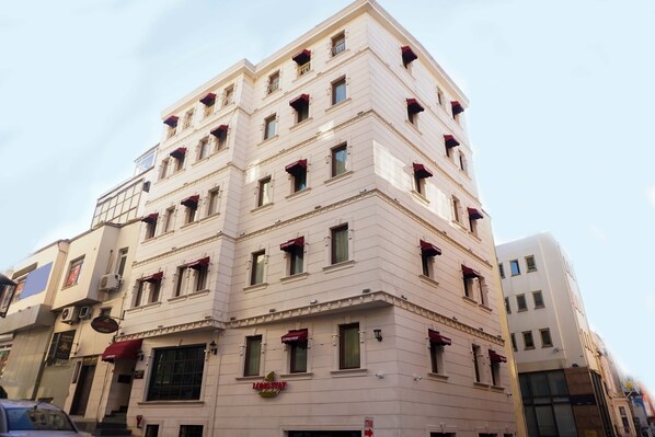 Um hotel com vários andares e design arquitetônico clássico, com uma placa chamativa "Long Stay" no andar térreo.