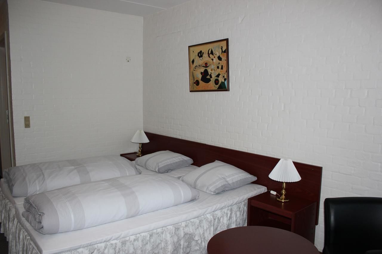 Quarto de hotel com uma cama grande, duas mesas de cabeceira, uma cadeira e um quadro na parede.