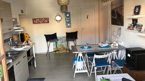 Uma cozinha compacta com área de refeições, um pequeno espaço de estar e uma porta que dá para outro quarto.