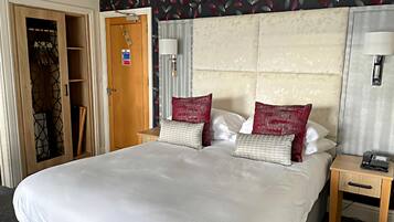 Quarto de hotel com uma cama grande, um guarda-roupa e uma mesa de cabeceira.