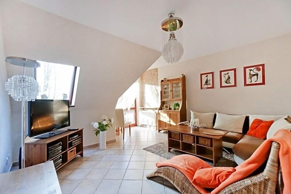 Uma sala de estar ampla com televisão, sofá e objetos decorativos.