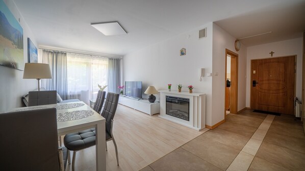 Uma sala de estar moderna com área de jantar, lareira e porta de madeira.