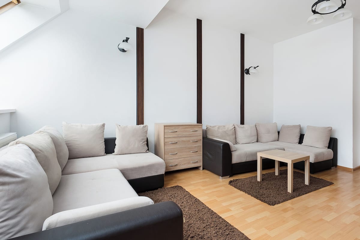 Uma sala de estar moderna com um sofá seccional, uma mesinha de centro e um armário de madeira.