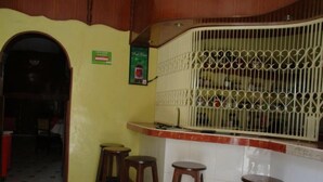 Uma área de bar com banquetas, balcão e grade metálica decorativa.