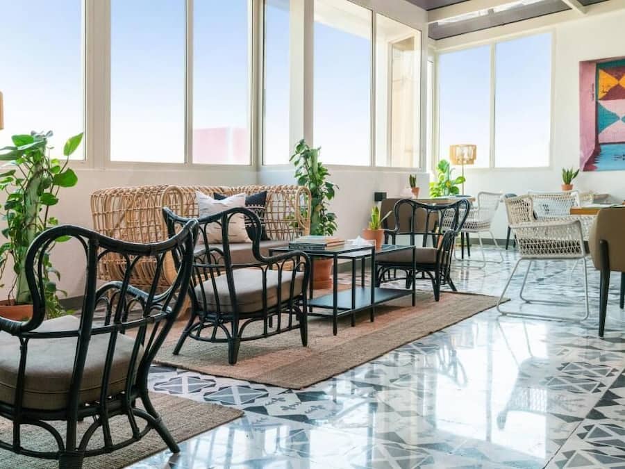 Um quarto espaçoso com janelas amplas, mobiliário de vime e piso em azulejo.