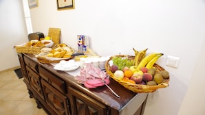 Uma mesa de buffet com diversos alimentos e uma cesta de frutas.