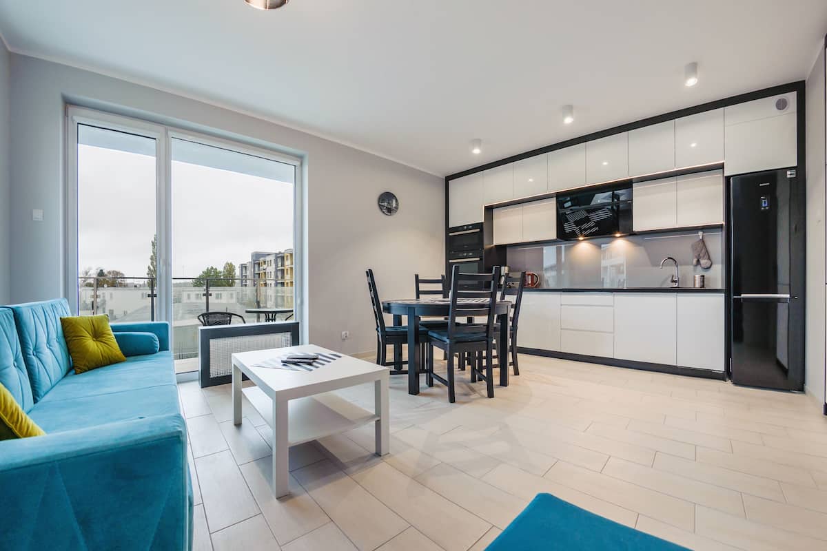 Um apartamento moderno com área de refeições, cozinha e uma janela ampla com vista para a cidade.