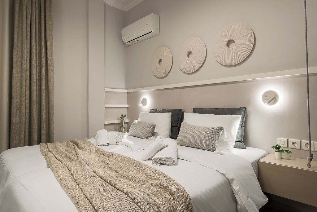 Quarto de hotel com uma cama grande, duas mesas de cabeceira, um aparelho de ar condicionado e três decorações circulares fixadas na parede.