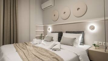 Quarto de hotel com uma cama grande, duas mesas de cabeceira, um aparelho de ar condicionado e três decorações circulares fixadas na parede.