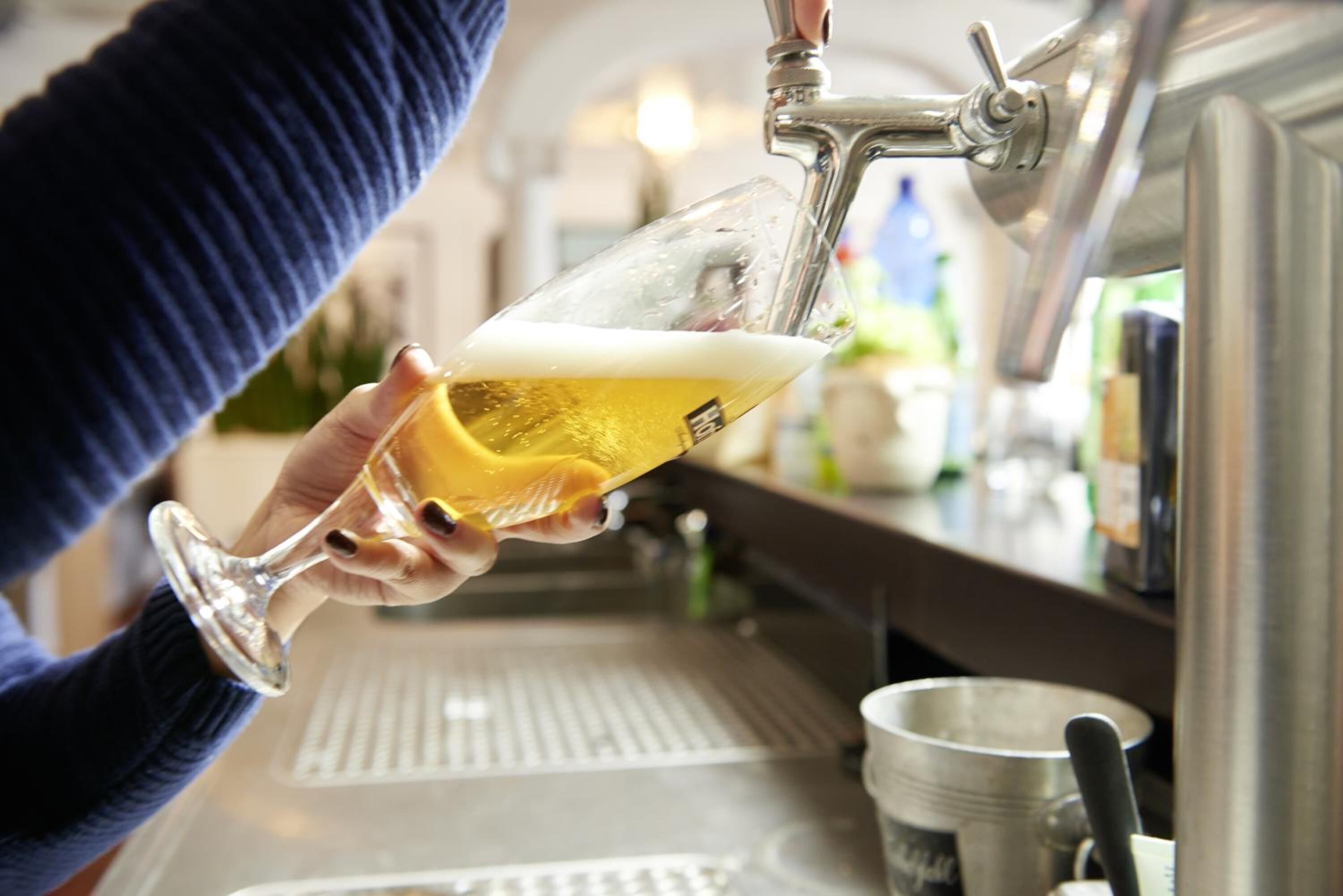 Uma pessoa segurando um copo de cerveja em um bar.