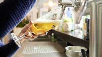 Uma pessoa segurando um copo de cerveja em um bar.