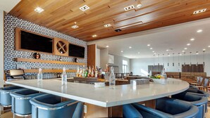 Cozinha moderna com ilha central, banquetas de bar e diversos eletrodomésticos.