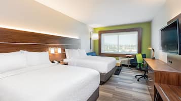 Quarto de hotel com duas camas, uma escrivaninha, uma cadeira, uma televisão e janela com vista.