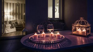 Uma mesa redonda com velas, copos de vinho e castiçal.