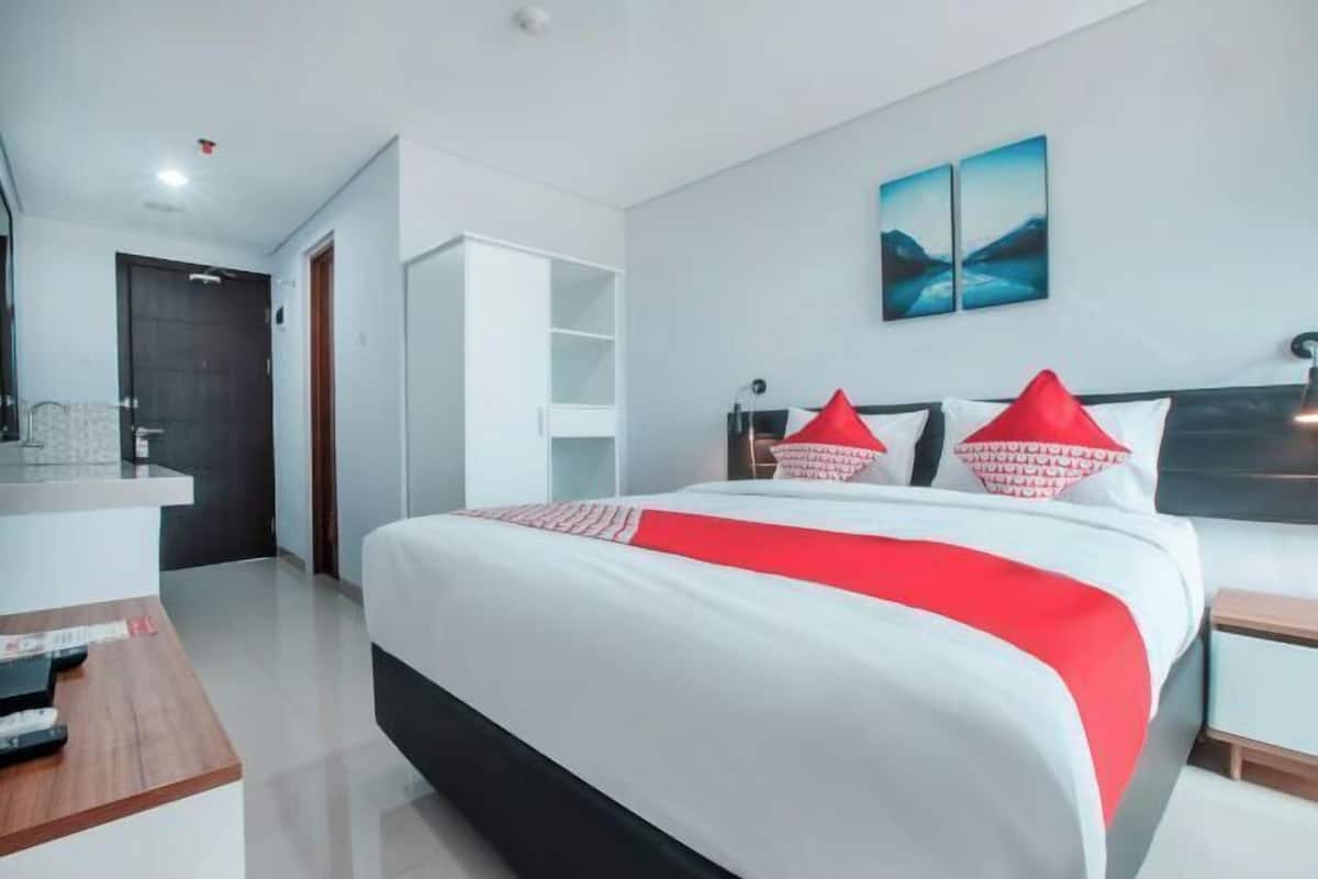 Quarto de hotel moderno com uma cama grande, uma escrivaninha, um guarda-roupa e um quadro na parede.