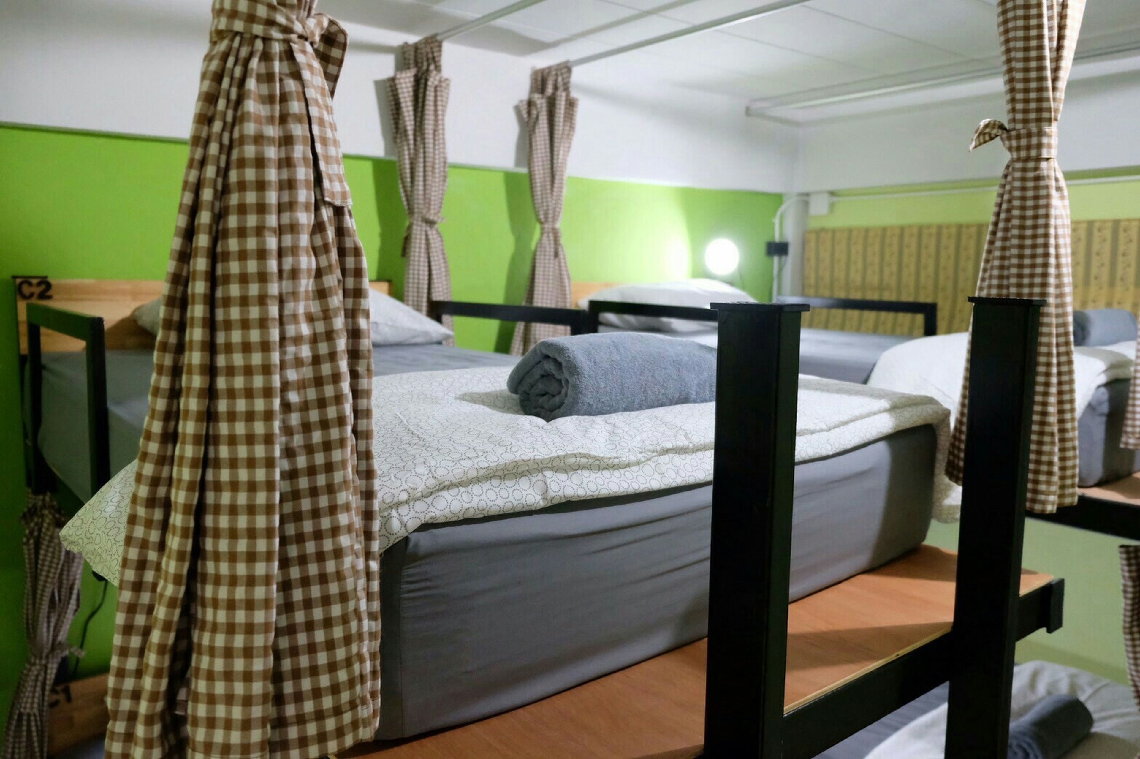 Um quarto de dormitório com beliches, cortinas xadrez e parede verde.