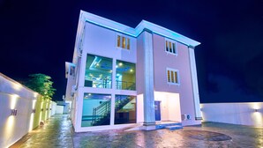 Um edifício moderno de dois andares, com fachada de vidro, escadaria que leva ao andar superior e entrada bem iluminada.