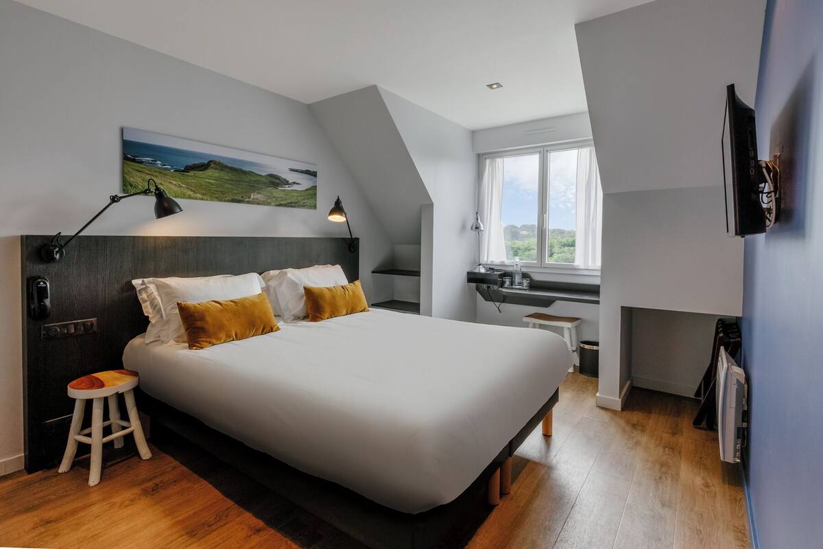 Quarto moderno com uma cama grande, uma escrivaninha e vista para o exterior.