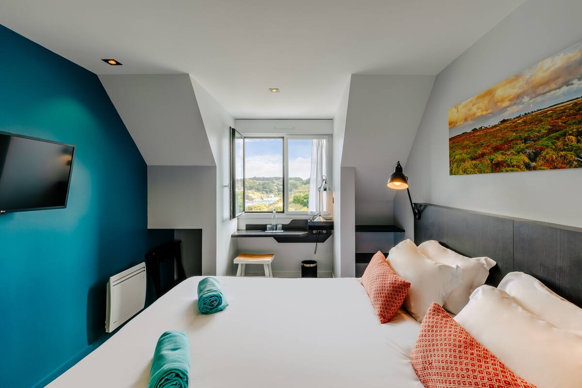 Quarto de hotel moderno com uma cama grande, uma escrivaninha e vista para o campo.