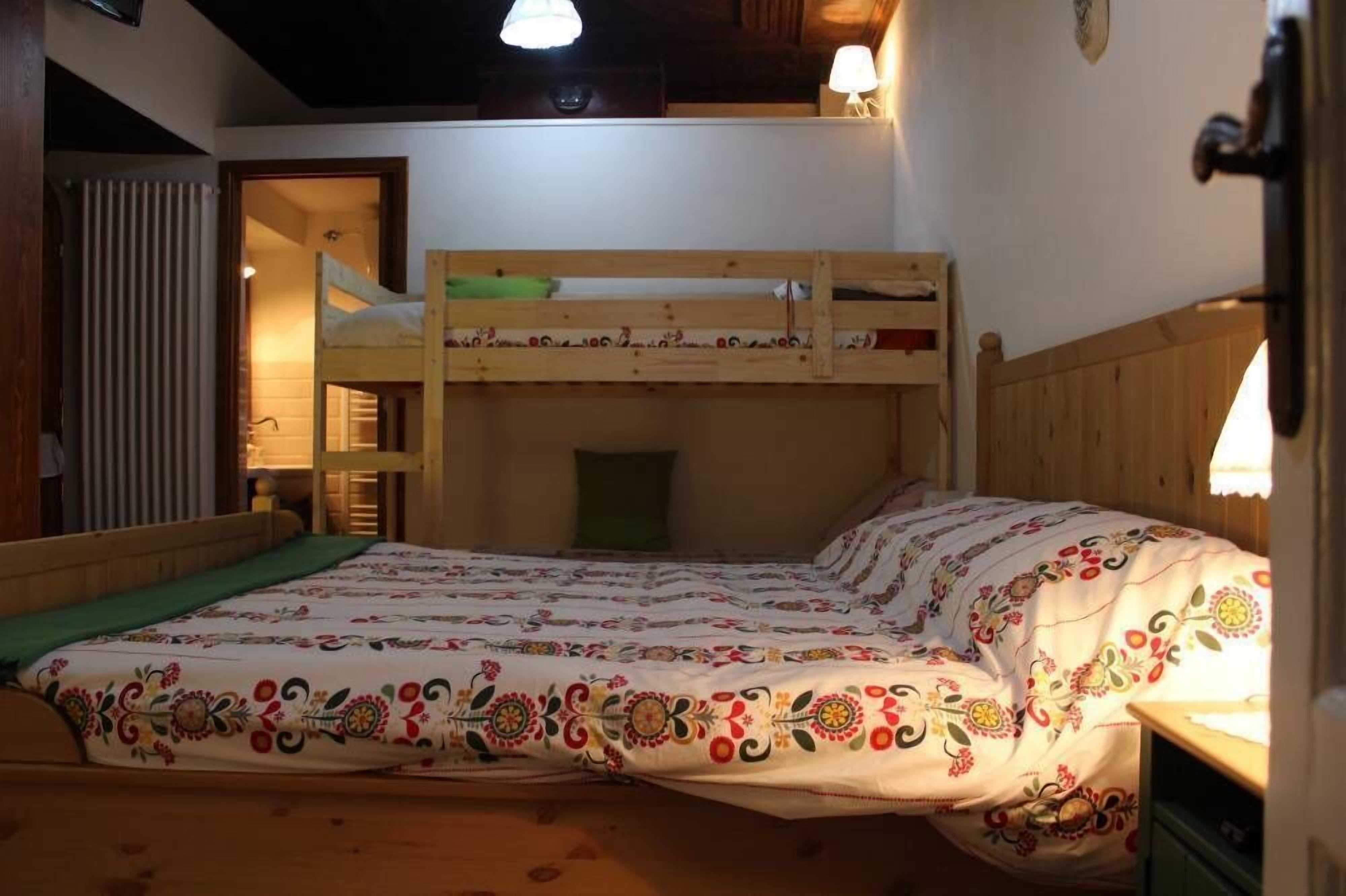 Quarto com beliche, cabeceira de madeira, travesseiro verde e colcha florida.