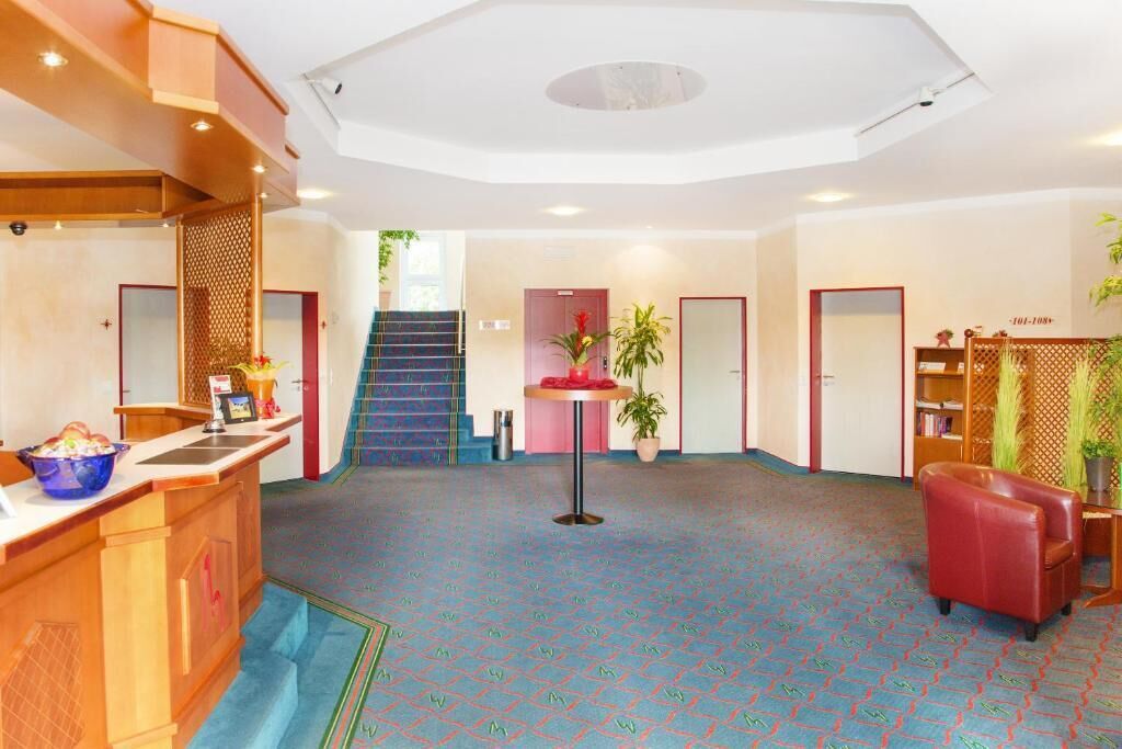 Um saguão de hotel com balcão de atendimento, escada e área de estar.