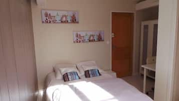 Quarto com cama, duas obras de arte na parede, porta de madeira e guarda-roupa branco.
