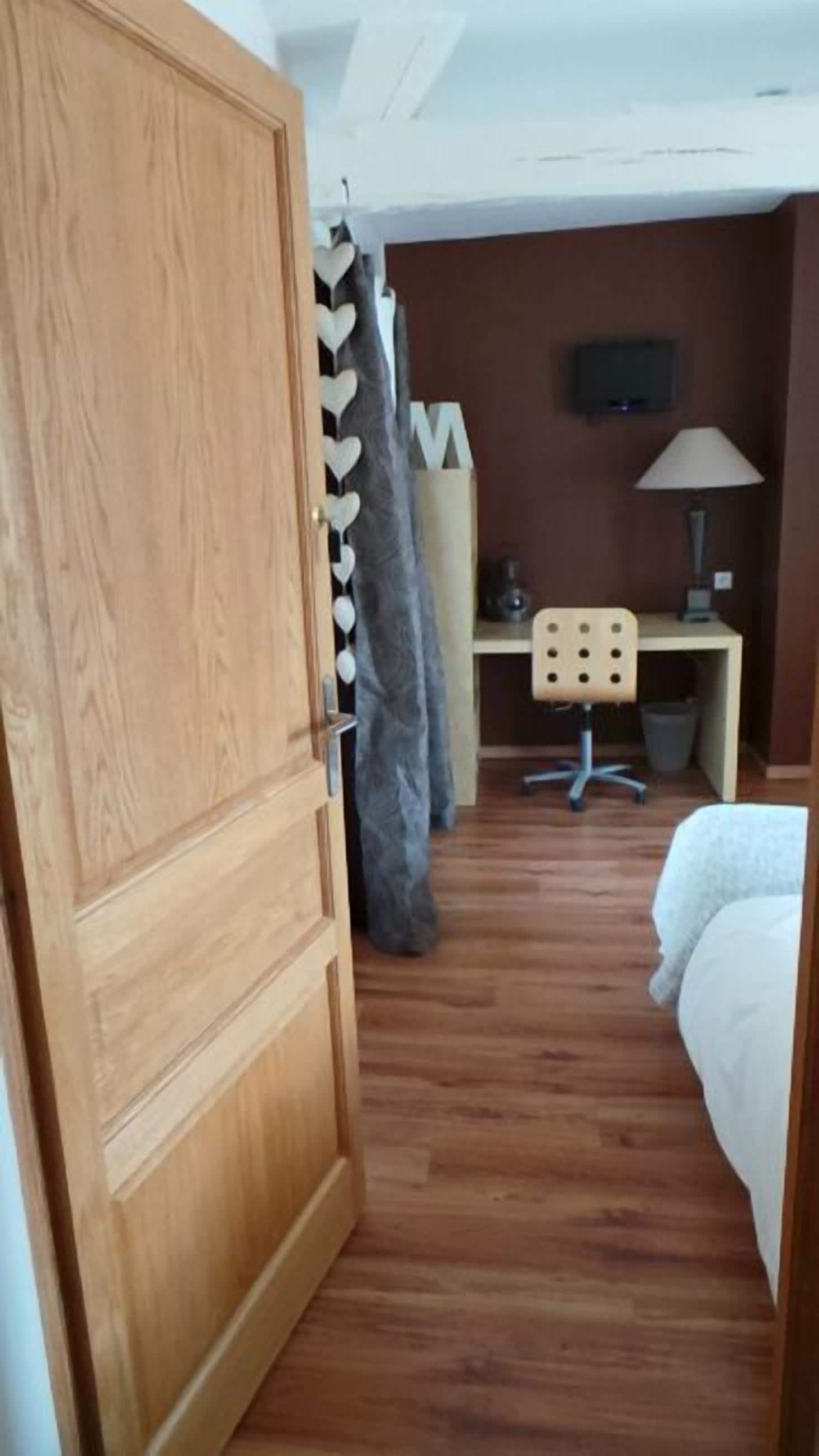 Quarto com guarda-roupa de madeira, escrivaninha com cadeira, cama e abajur.