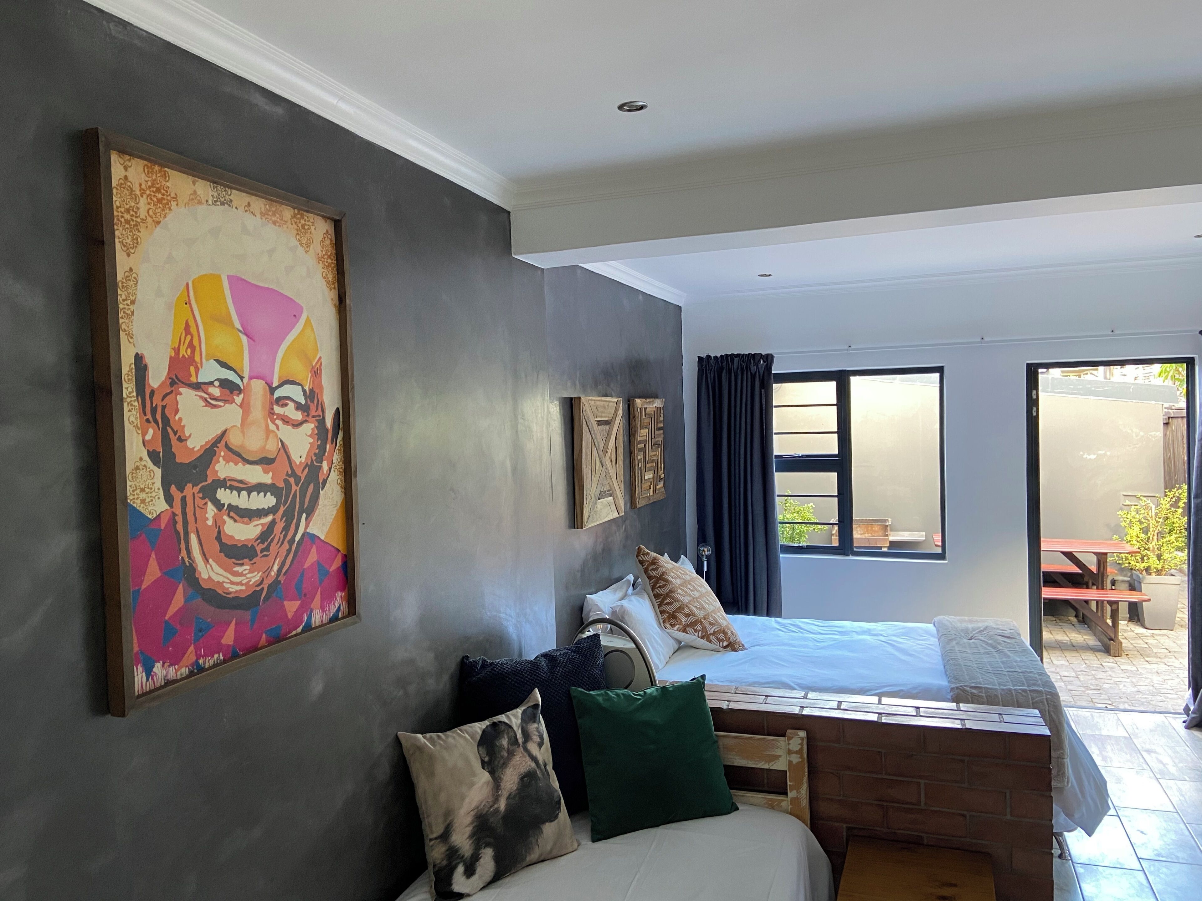 Quarto com cama, travesseiros, uma pintura grande e uma janela.