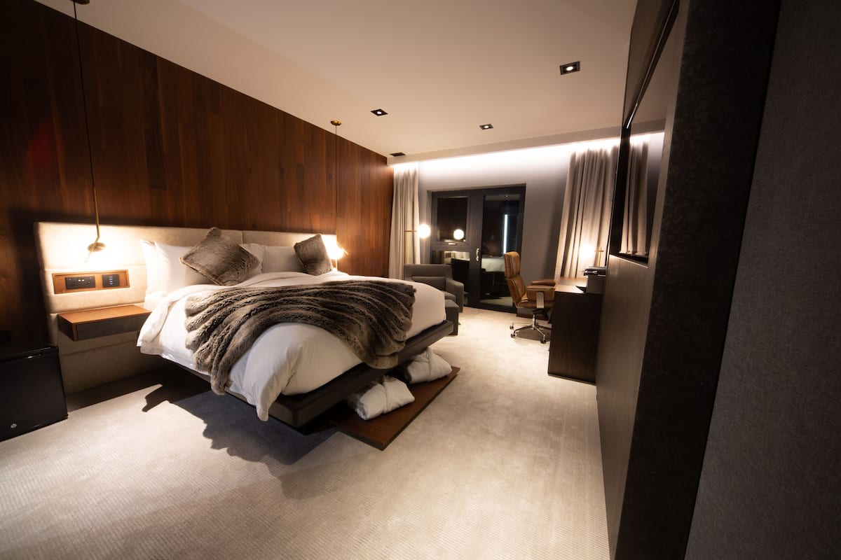 Quarto moderno com uma cama grande, mesas de cabeceira, uma escrivaninha e uma cadeira.