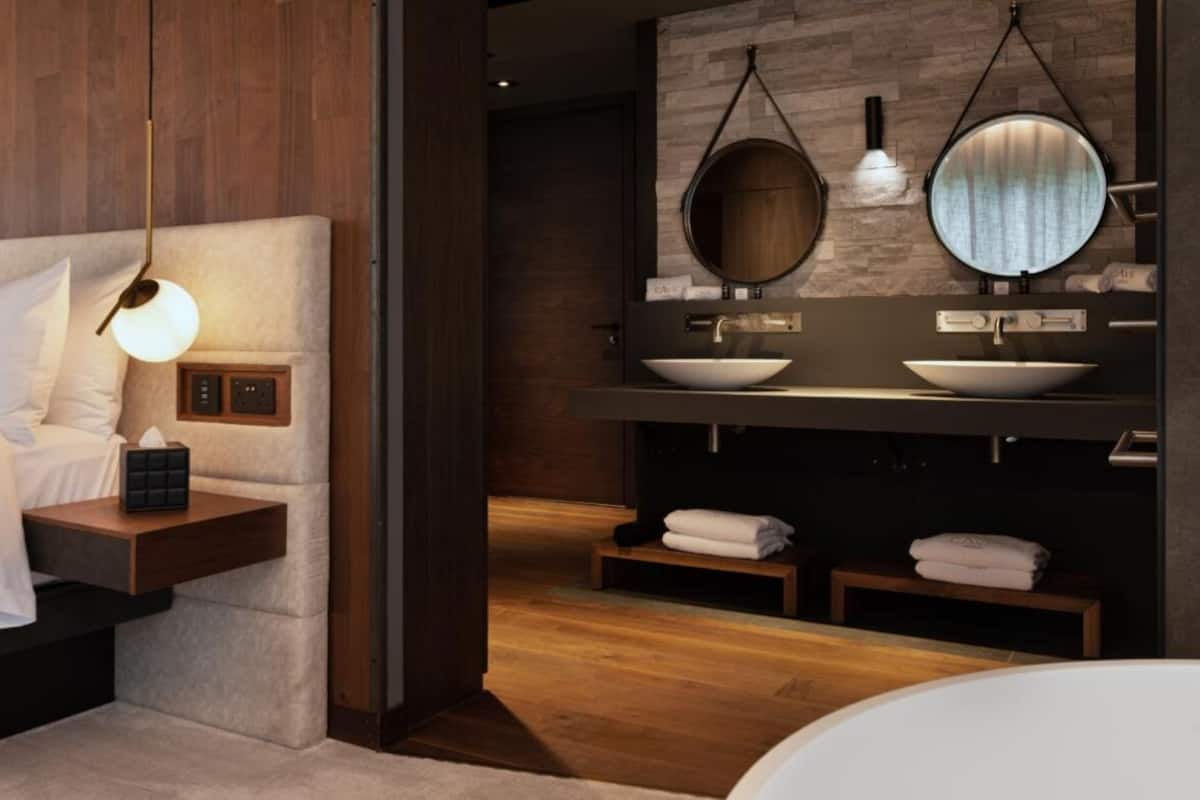 Uma casa de banho moderna com um espelho grande, duas lavatórios e uma mesa de cabeceira com uma lâmpada.