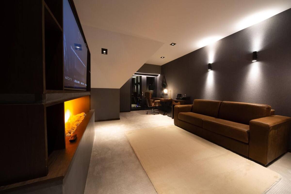Uma sala de estar moderna com uma TV de tela plana, um sofá de couro marrom e um tapete grande.