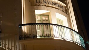 Um edifício com a placa "LE BALMORAL" iluminada durante a noite.