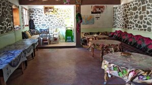 Um quarto acolhedor com parede de pedra, um sofá, uma mesa de jantar e uma cadeira.