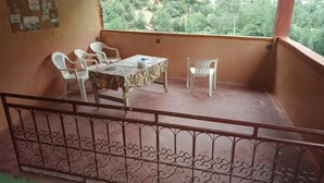 Uma varanda com mesa e cadeiras, vista para o verde e um mural na parede.