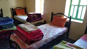 Quarto tipo dormitório com duas camas de solteiro, cada uma com travesseiro e cobertor.