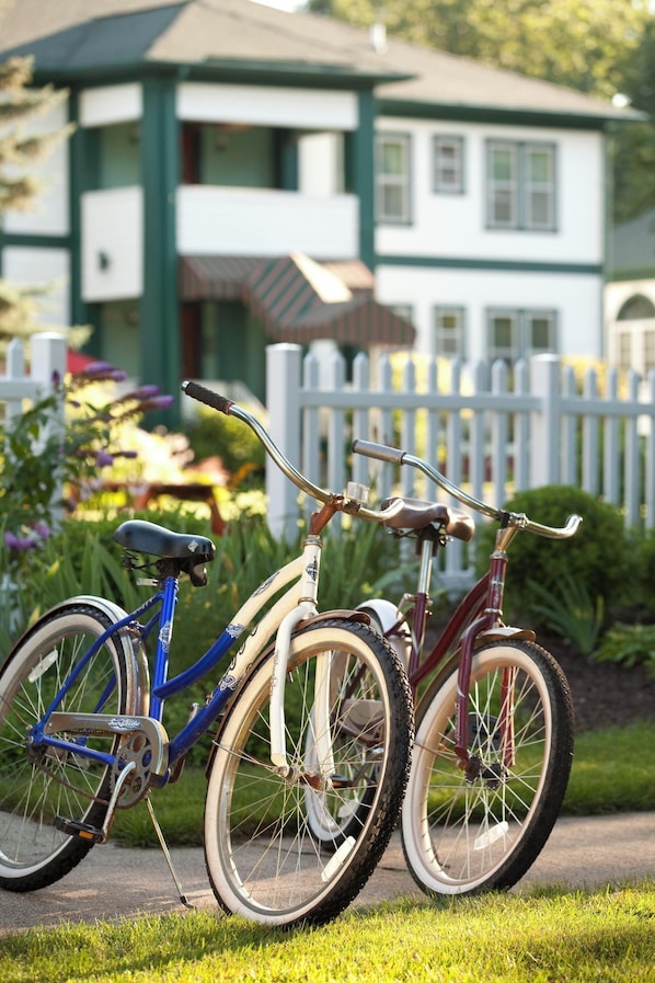 Uma bicicleta estacionada em frente a uma casa com cerca branca e um jardim.