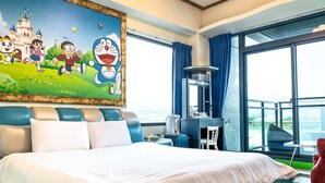 Quarto de hotel com uma cama grande, uma escrivaninha, uma cadeira e um quadro com personagens de desenho animado.