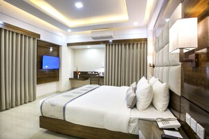 Quarto de hotel moderno com uma cama grande, uma escrivaninha e uma televisão.