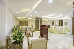 Um amplo saguão de hotel com área de estar, palco e mesas montadas para refeições.
