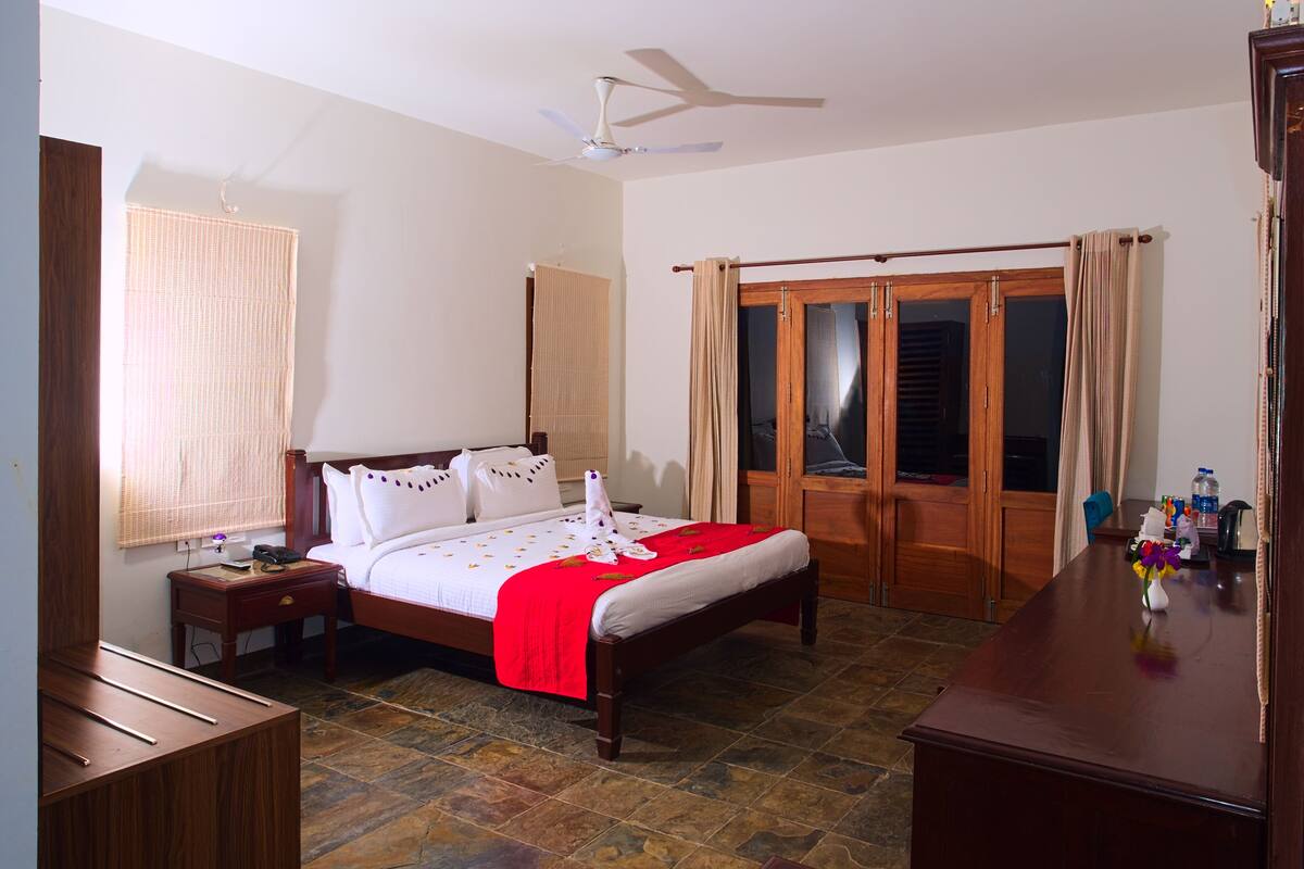 Quarto bem arrumado com cama, mesas de cabeceira, escrivaninha e guarda-roupa.