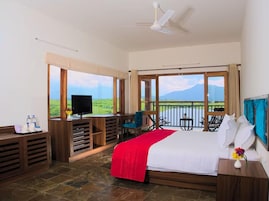 Quarto com uma cama grande, televisão, varanda com vista para a paisagem e área de estar com cadeiras.